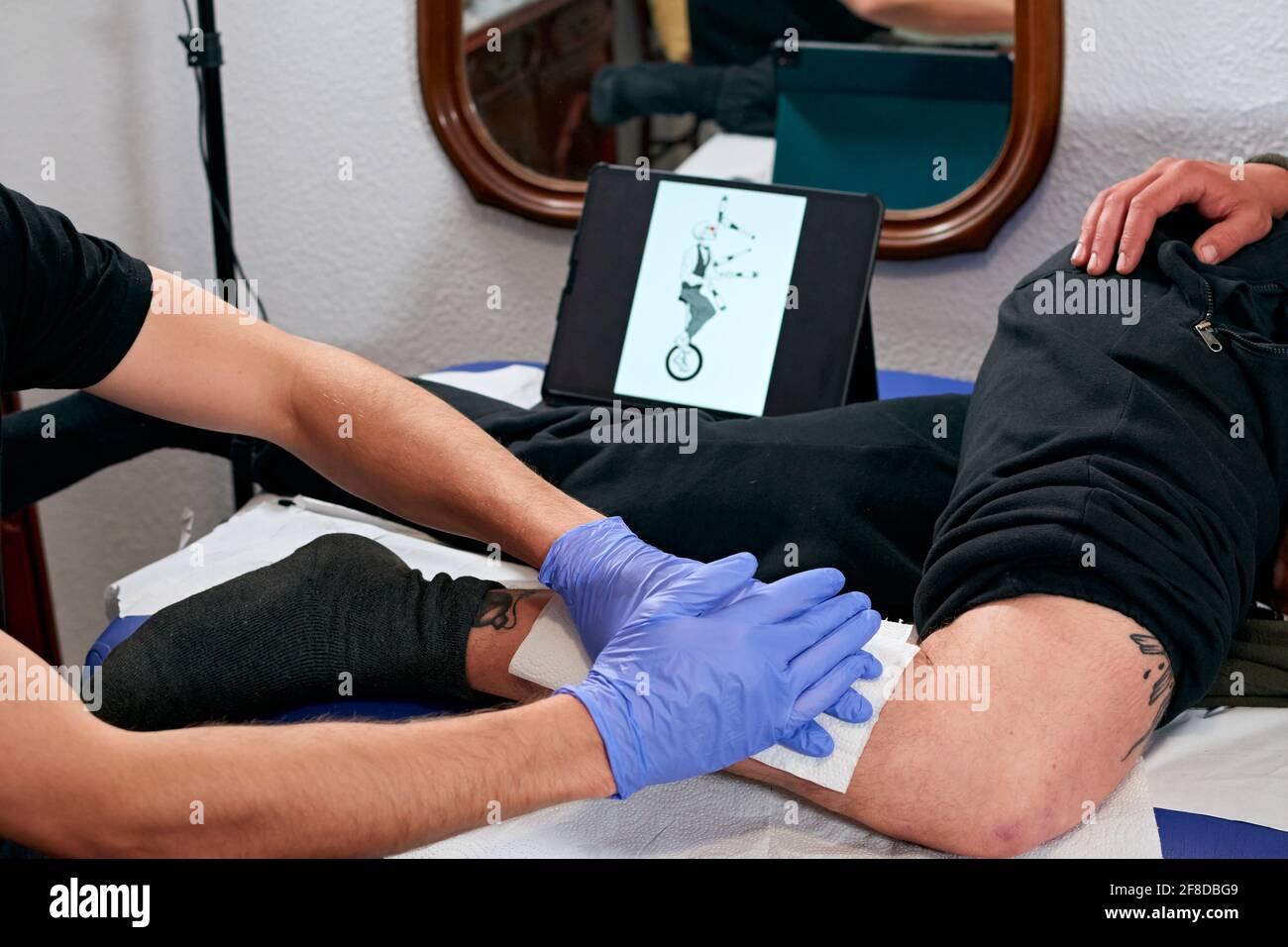 Hands of a tattoo artist in blue gloves cleaning the newly completed ...