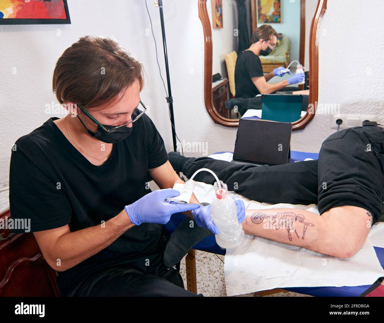 Tattoo artist in blue gloves cleaning the newly completed tattoo on a ...