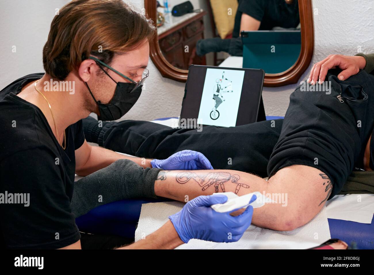 Tattoo artist in blue gloves cleaning the newly completed tattoo on a ...