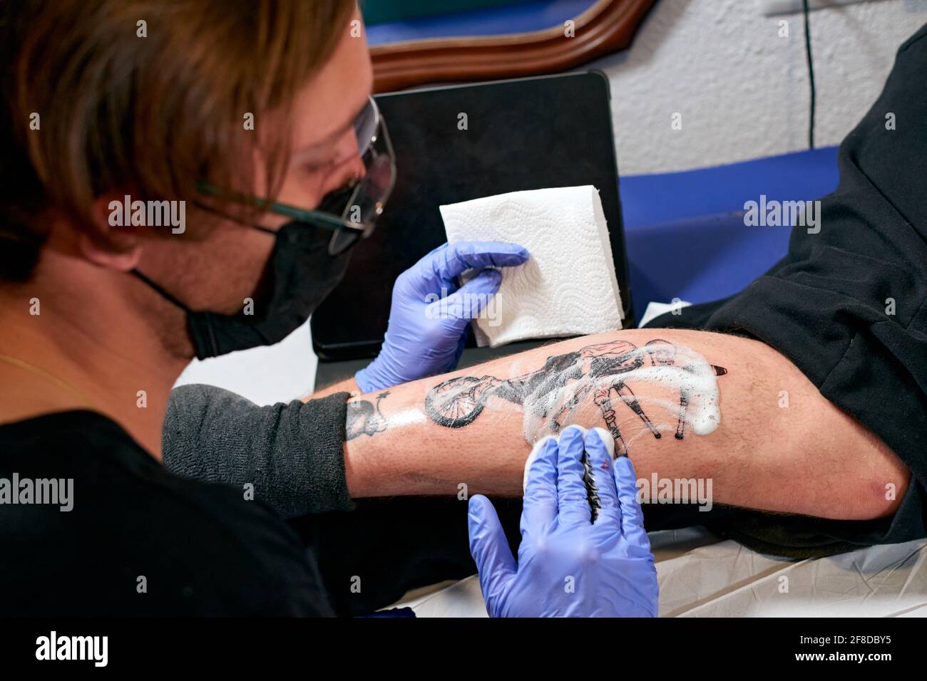 Tattoo artist in blue gloves cleaning the newly completed tattoo on a ...