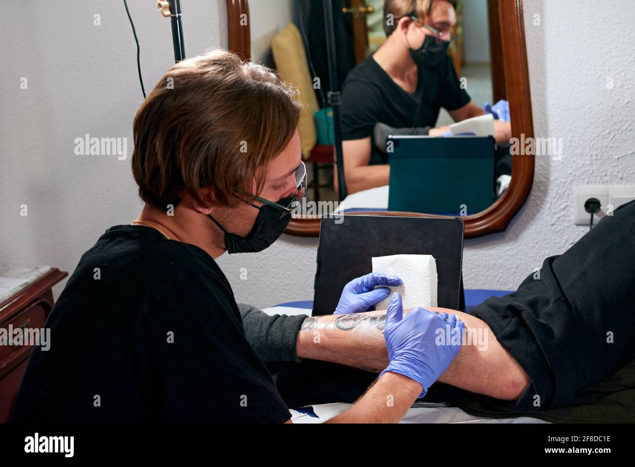 Tattoo artist in blue gloves cleaning the newly completed tattoo on a ...