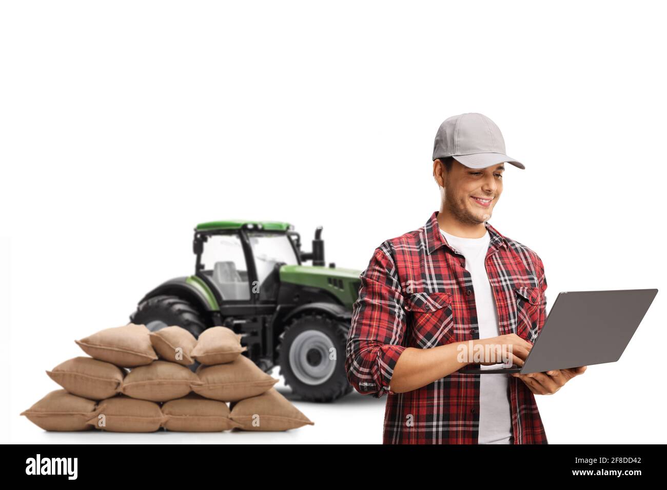 Farmer with a tractor working on a laptop computer isolated on white ...
