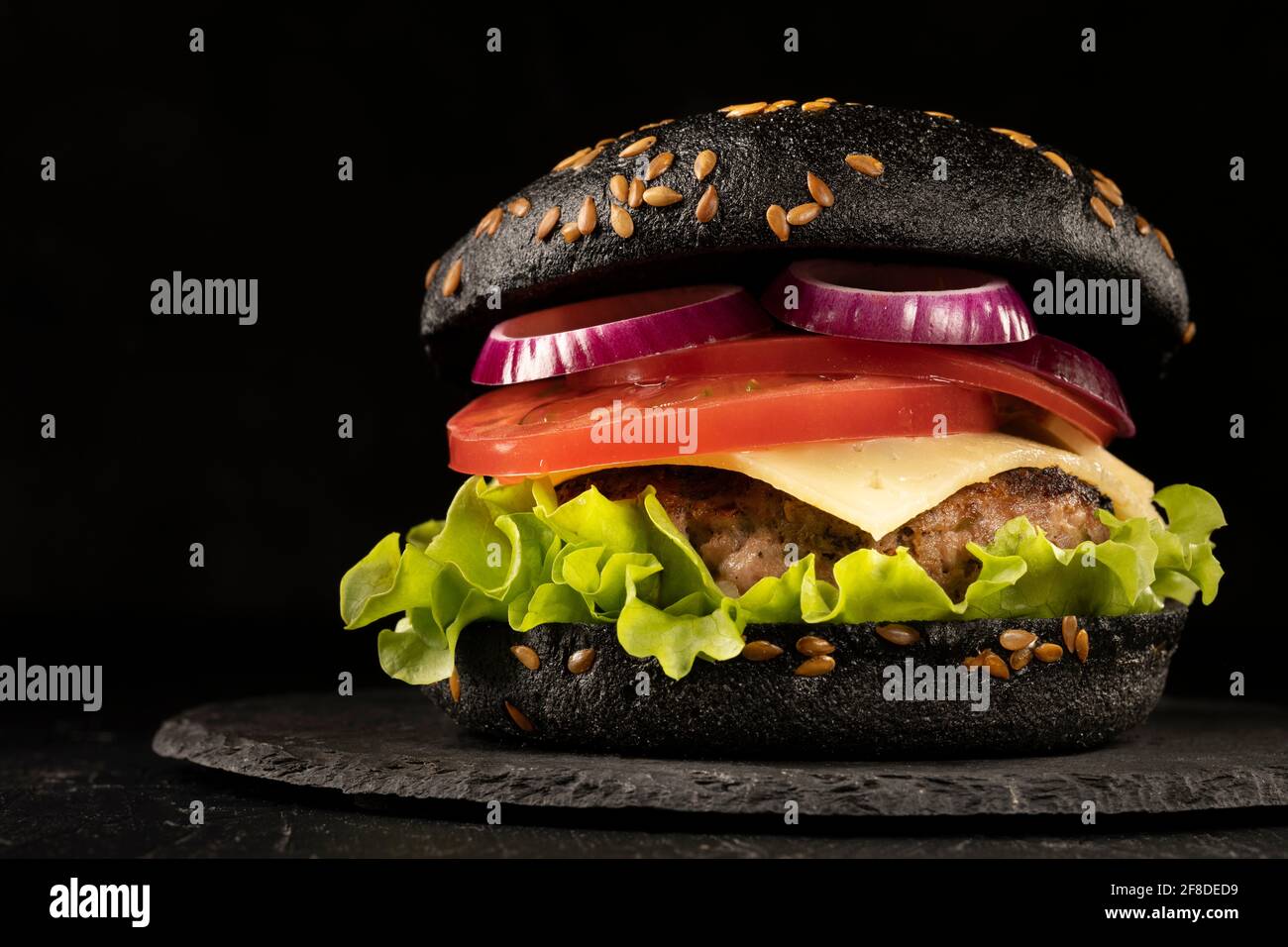Beef burger with a black bun on a dark background Stock Photo - Alamy