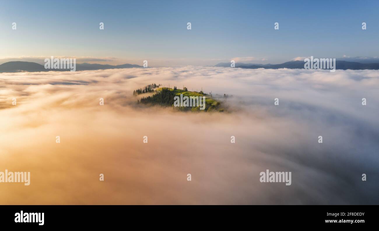 Mountains in clouds at sunrise in summer. Aerial view of mountain peak ...