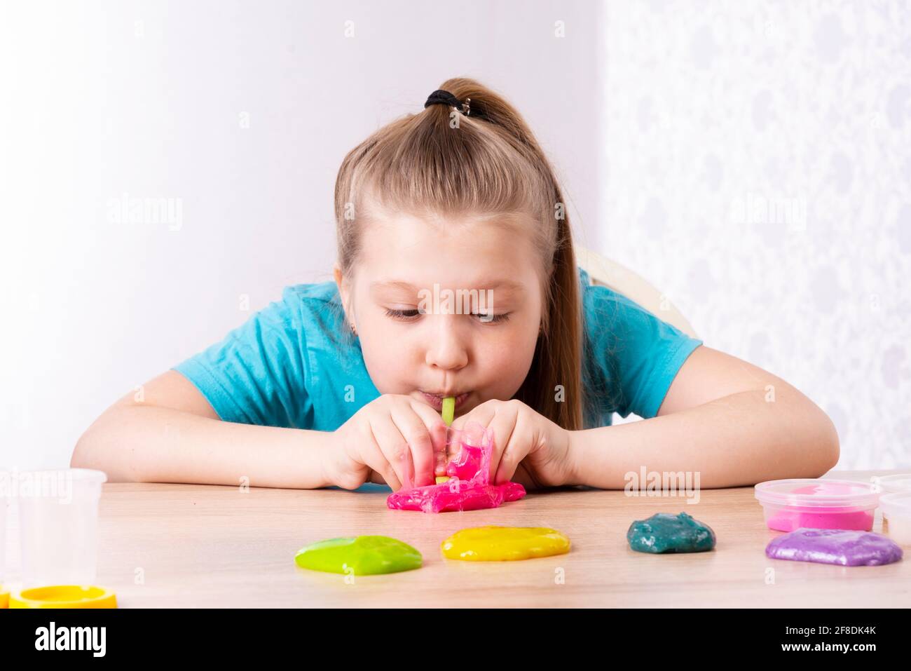 A blonde child blows a slime bubble. Play a slime toy. Making slime at ...