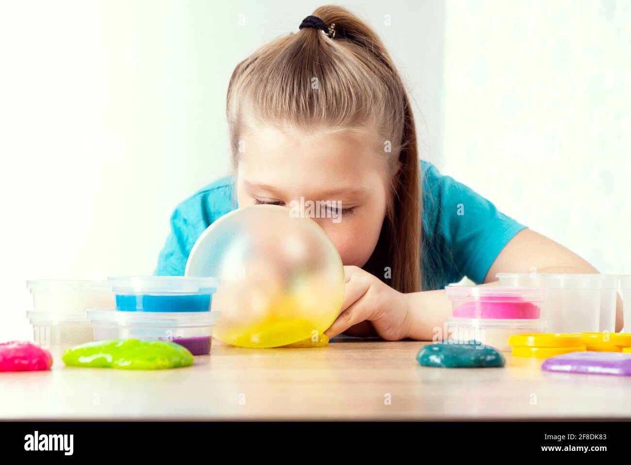 A blonde child inflates a bottle of yellow slime. Play a slime toy ...