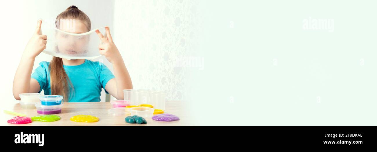 A blonde child is playing with a slime. Little beautiful caucasian girl ...