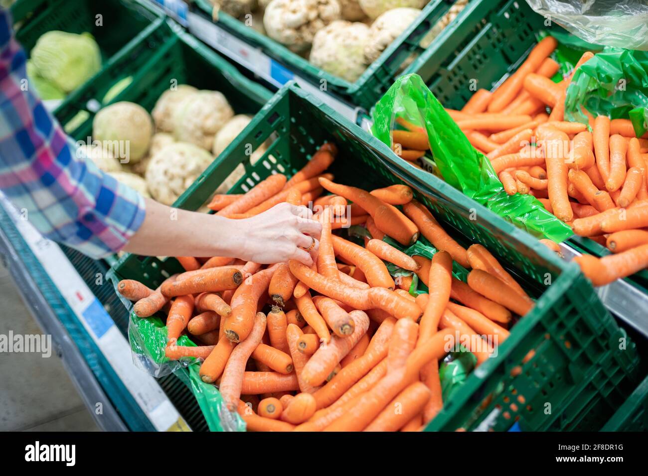 Woman,s hand choosing bio carrot in vegetable store or supermarket ...