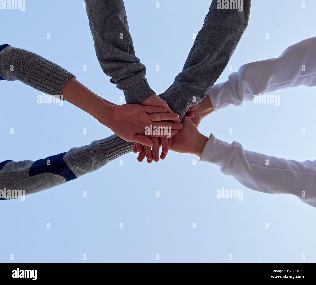 Low angle shot of three young friends putting their hands together ...
