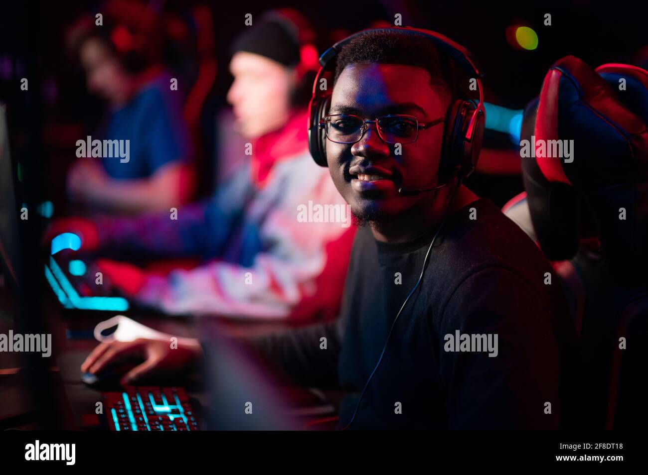 Neon light in the arena at the online shooter tournament. A young black ...