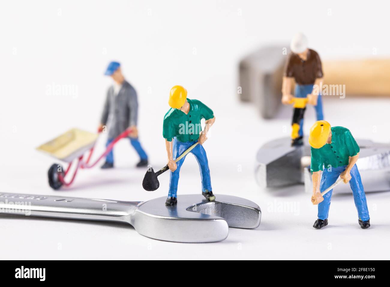 Soft focus of miniature toy construction workers on life-size tools ...