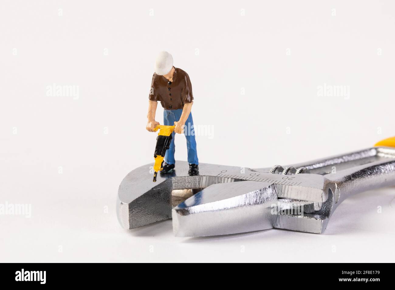 Closeup of a small plastic construction worker toy on a wrench isolated ...