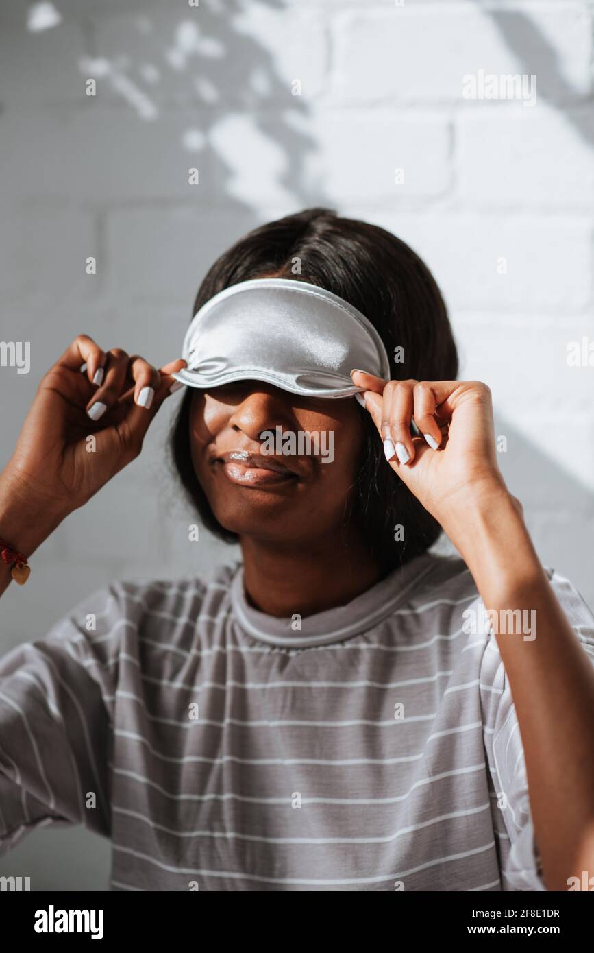 Happy smiling African female in a white sleeping eye mask sitting on ...