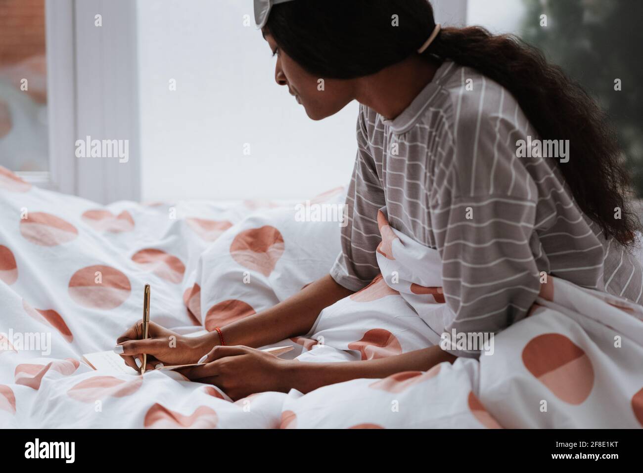 Pretty young African female writing notes while sitting on bed Stock ...