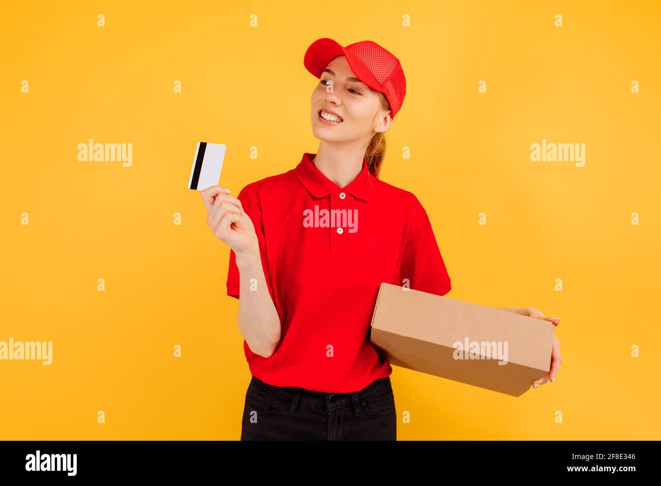 Happy young woman courier, in red uniform, delivery officer holding ...