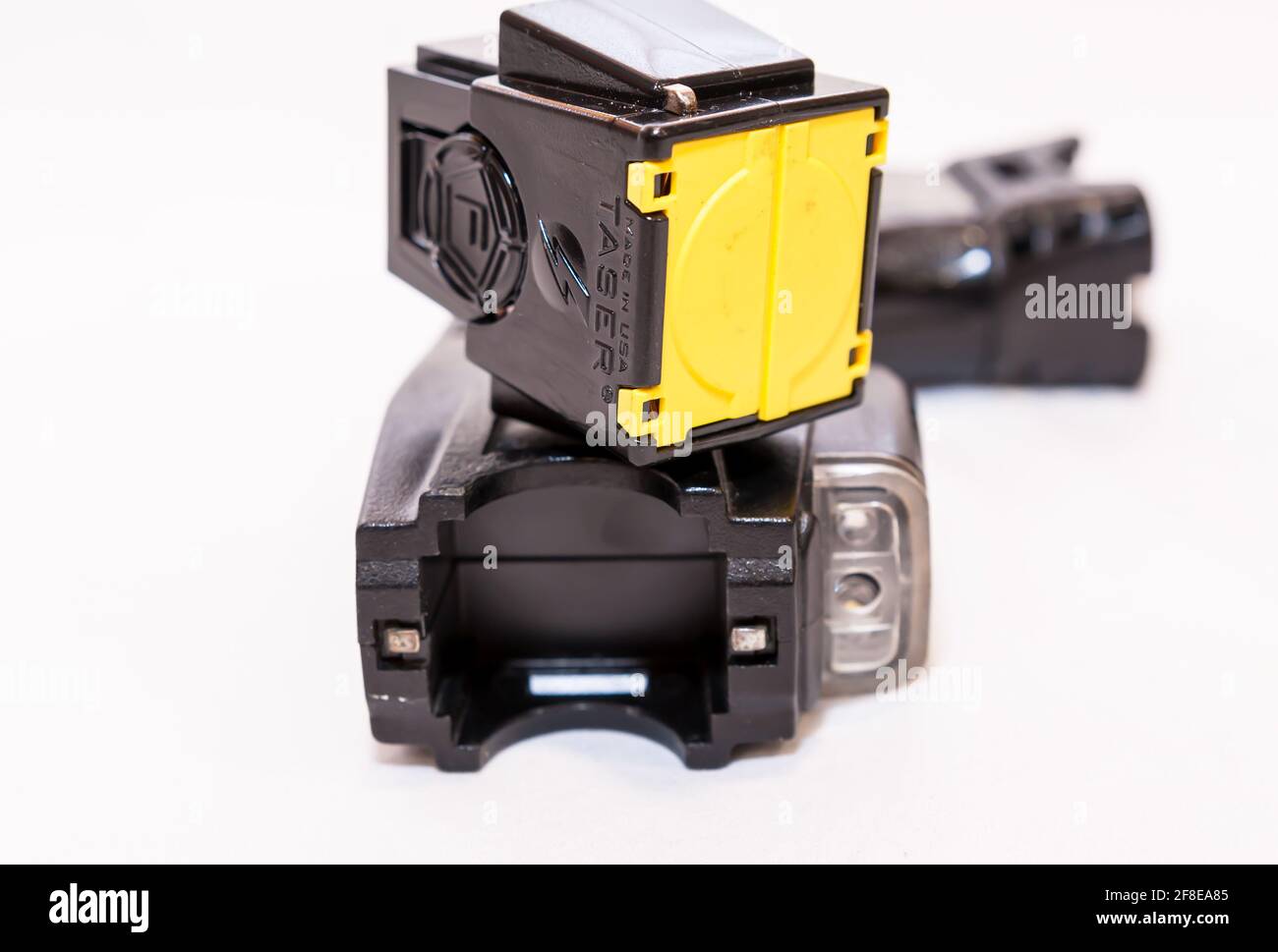 X26 taser with an unloaded yellow cartridge laying on top of it on a ...