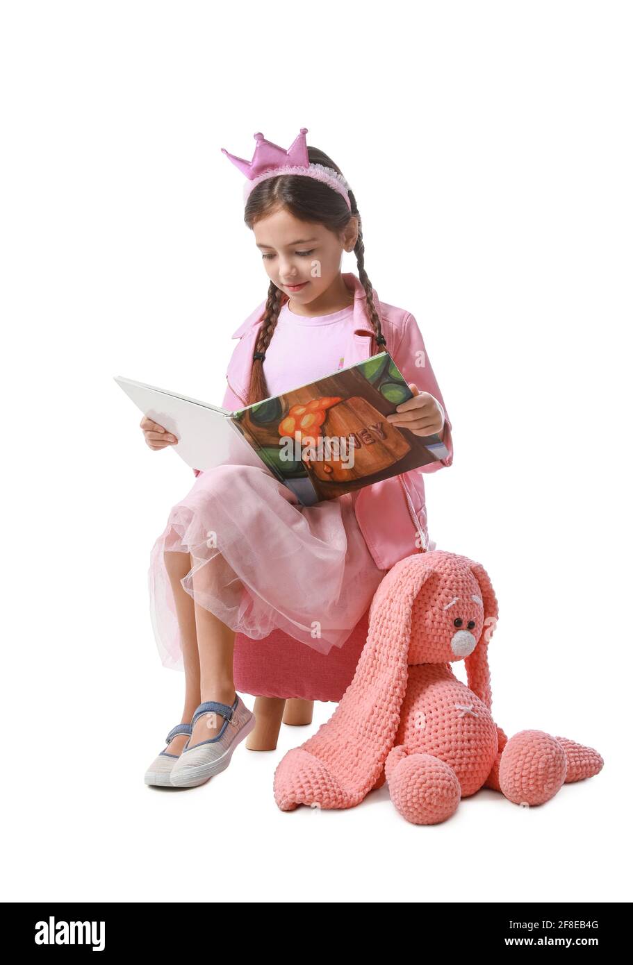 Cute little princess with book and toy on white background Stock Photo ...