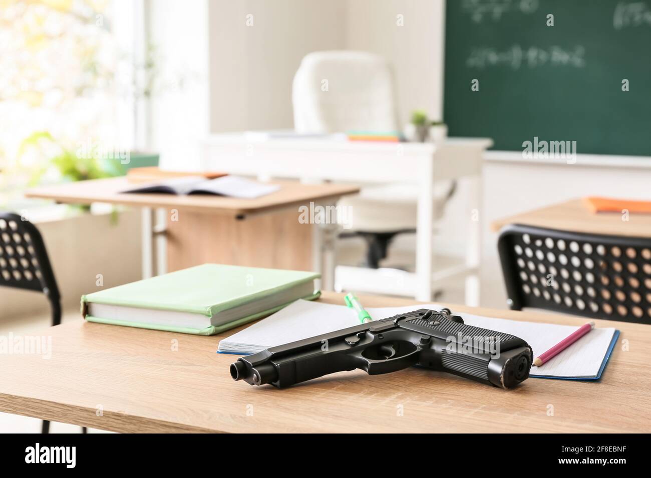 Gun on desk in classroom. Problem of shooting at school Stock Photo - Alamy