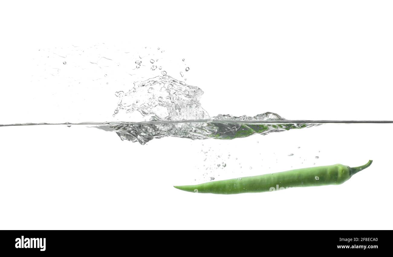 Falling of fresh chili pepper into water against white background Stock ...
