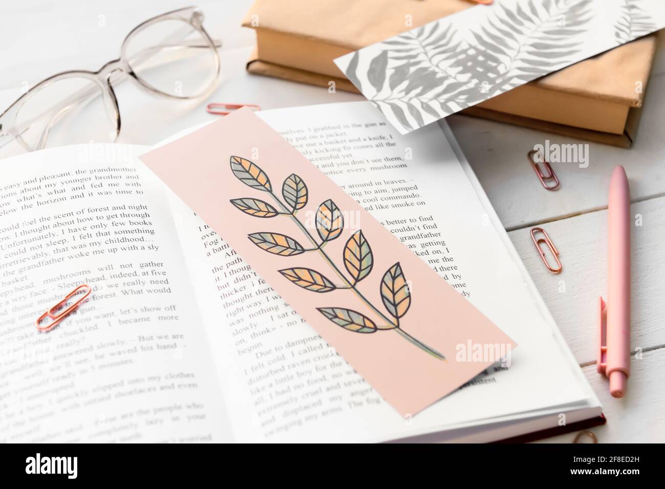 Books with bookmarks, glasses and stationery on light wooden background ...