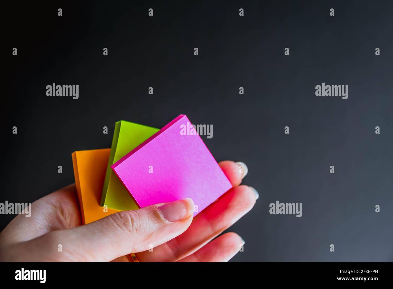 Hand with colorful notes on black background Stock Photo - Alamy