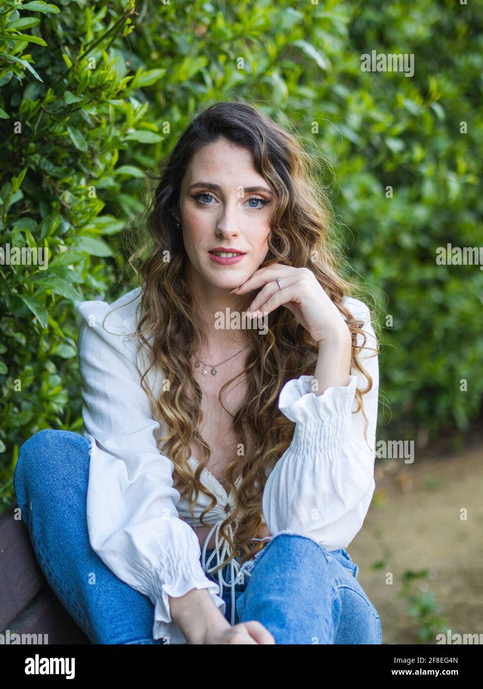 Young pretty long-haired female wearing a white blouse and jeans is ...