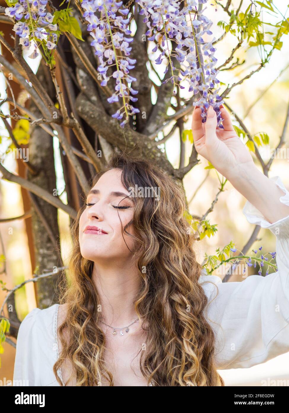 Pretty young long-haired female with eyes closed is posing under the ...