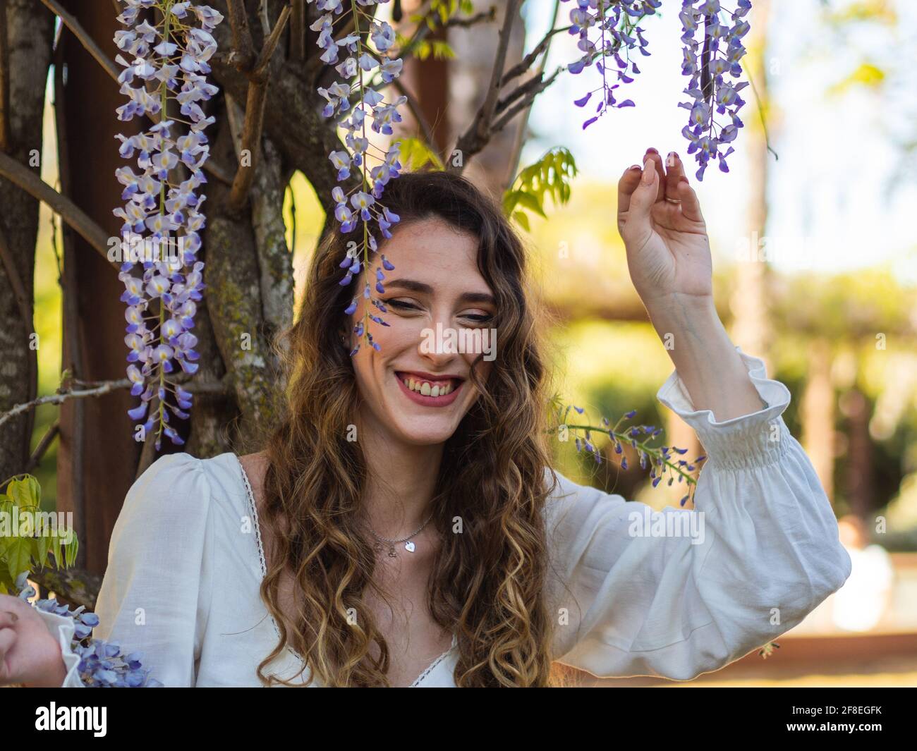 Young happy female wearing a white blouse is posing under a violet ...