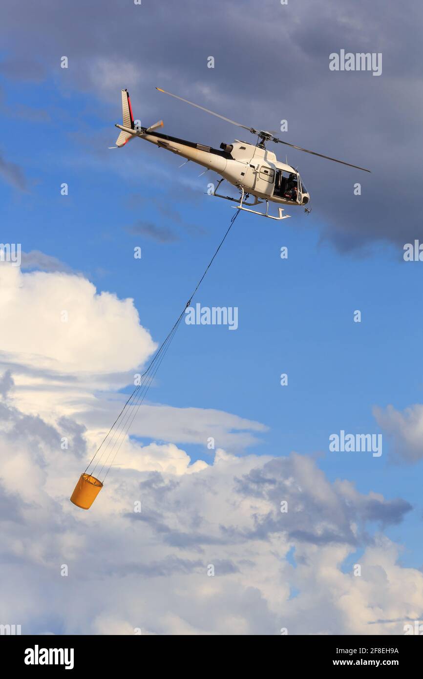 A firefighting helicopter trailing a monsoon bucket full of water on a ...