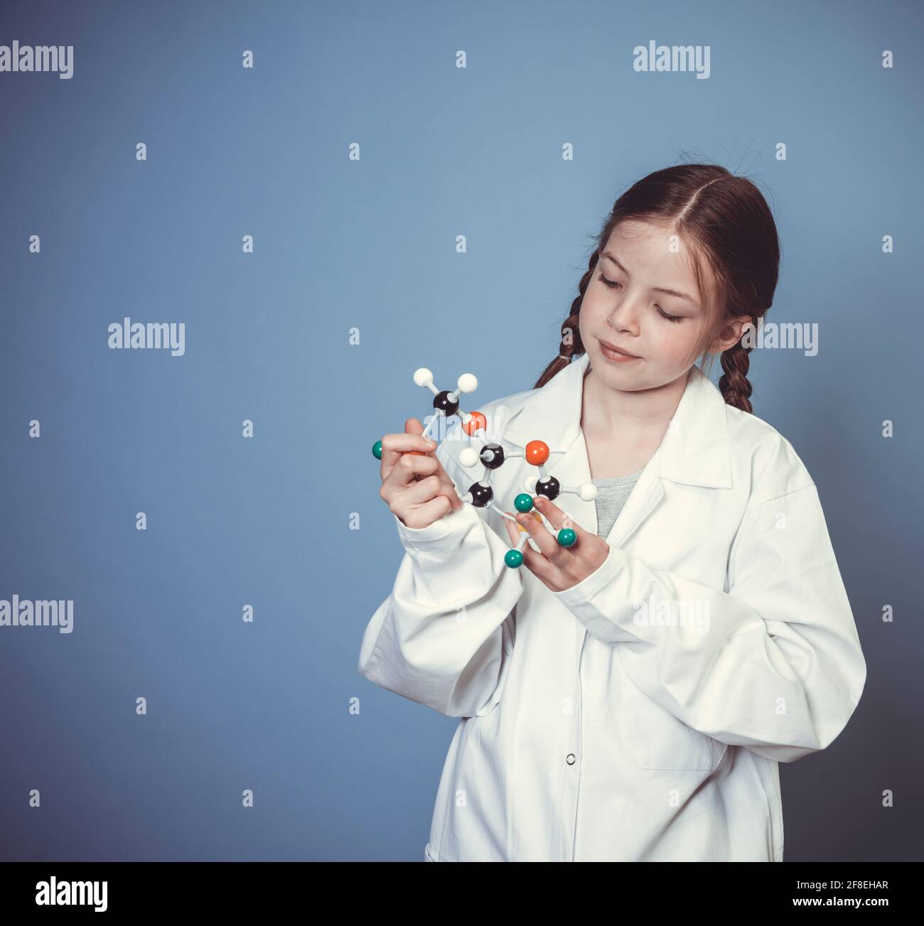 pretty girl with two braids is dressed as scientist and holds model of ...