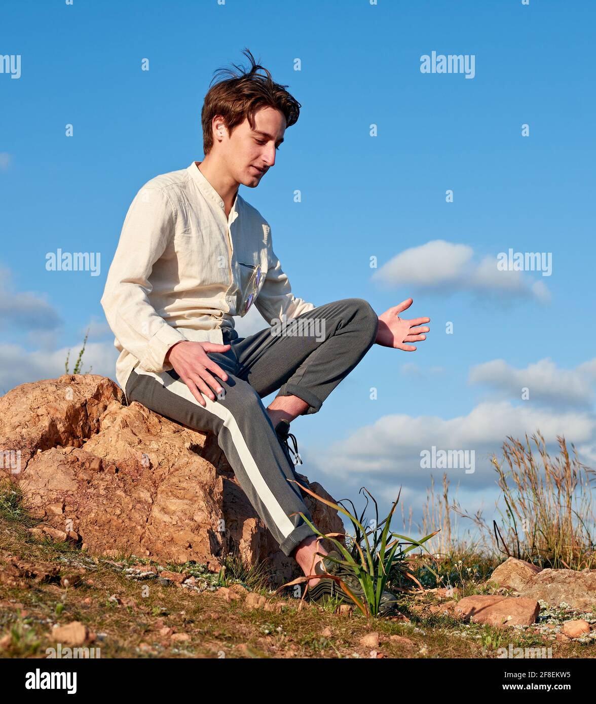 Side view of a young Spanish handsome male sitting on the rock against ...
