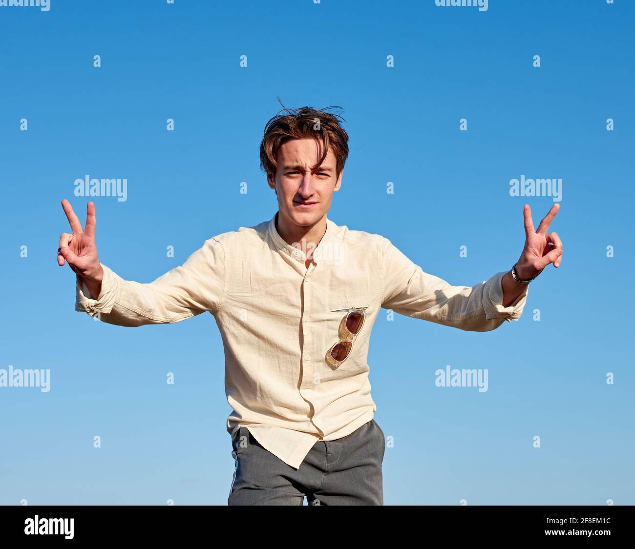Vertical of a young Spanish handsome male showing the peace sign ...