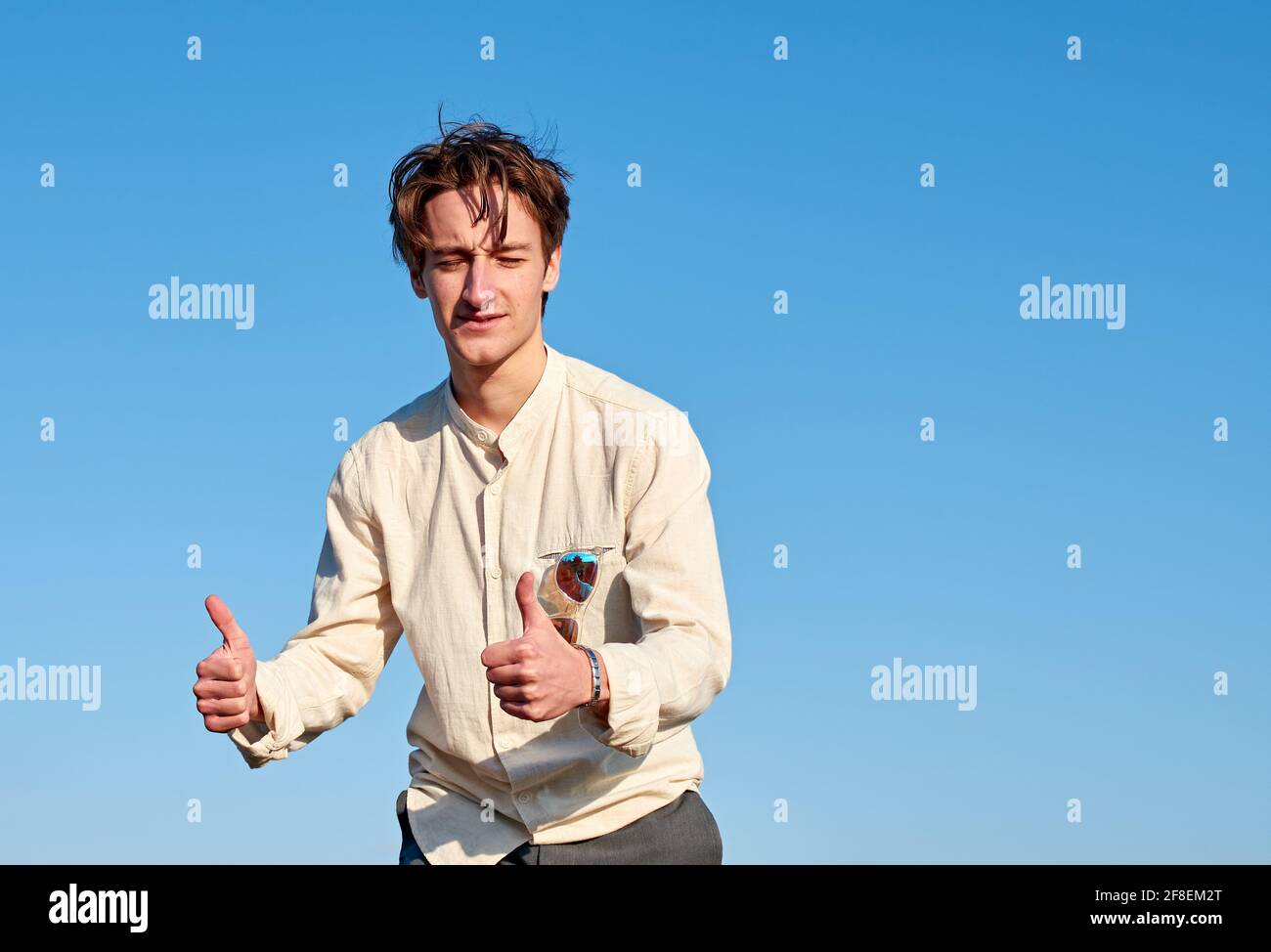 Vertical of a young Spanish handsome male giving thumbs up against the ...