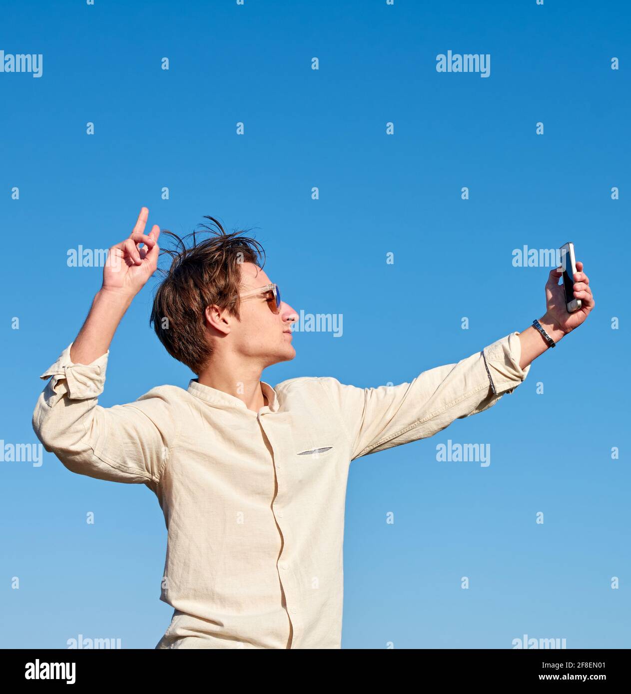Side view of a young handsome Spanish male taking a selfie with a ...