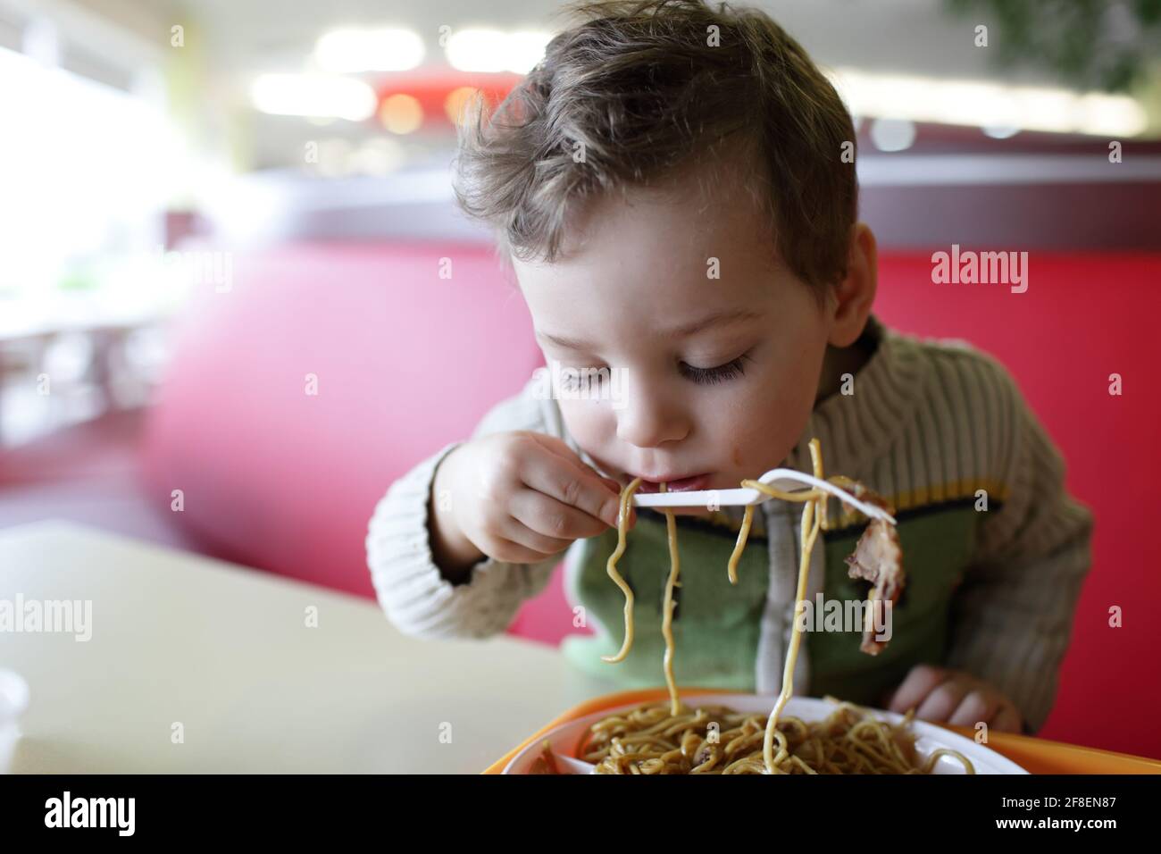 The boy eating spaghetti in the restaurant Stock Photo - Alamy