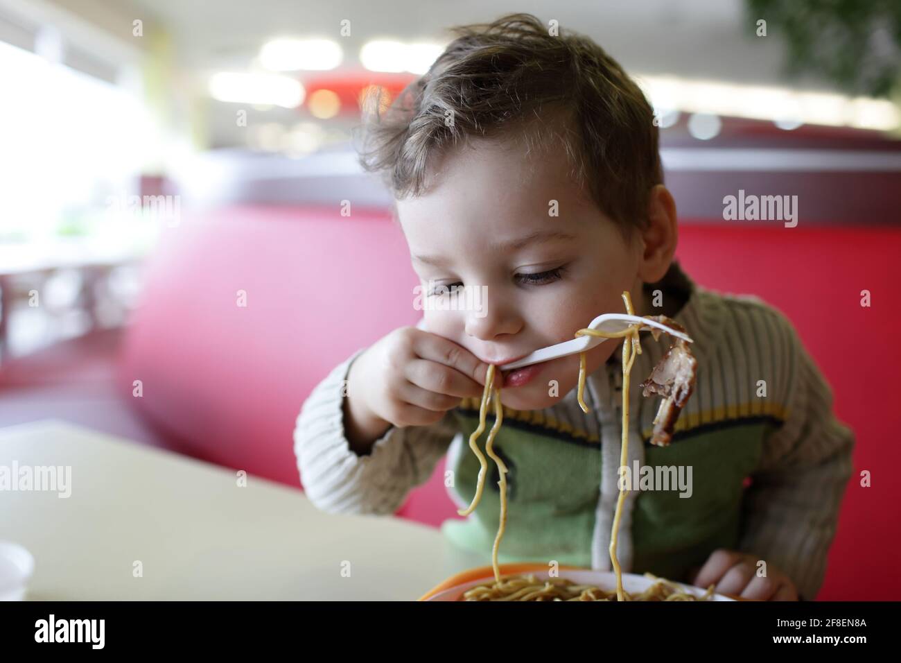 The child eating spaghetti in the restaurant Stock Photo - Alamy