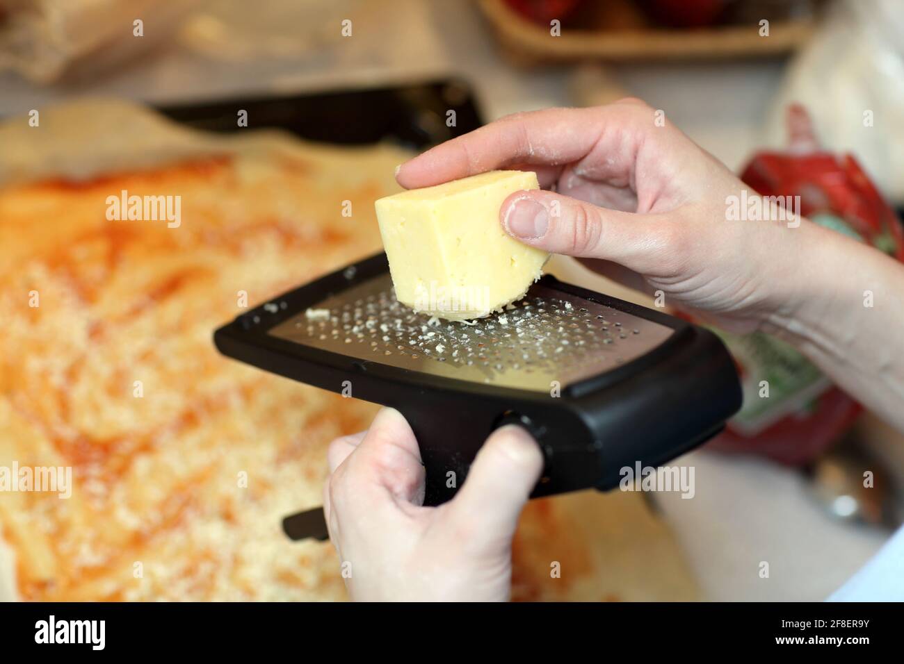 Chef grating cheese onto pizza at home Stock Photo - Alamy