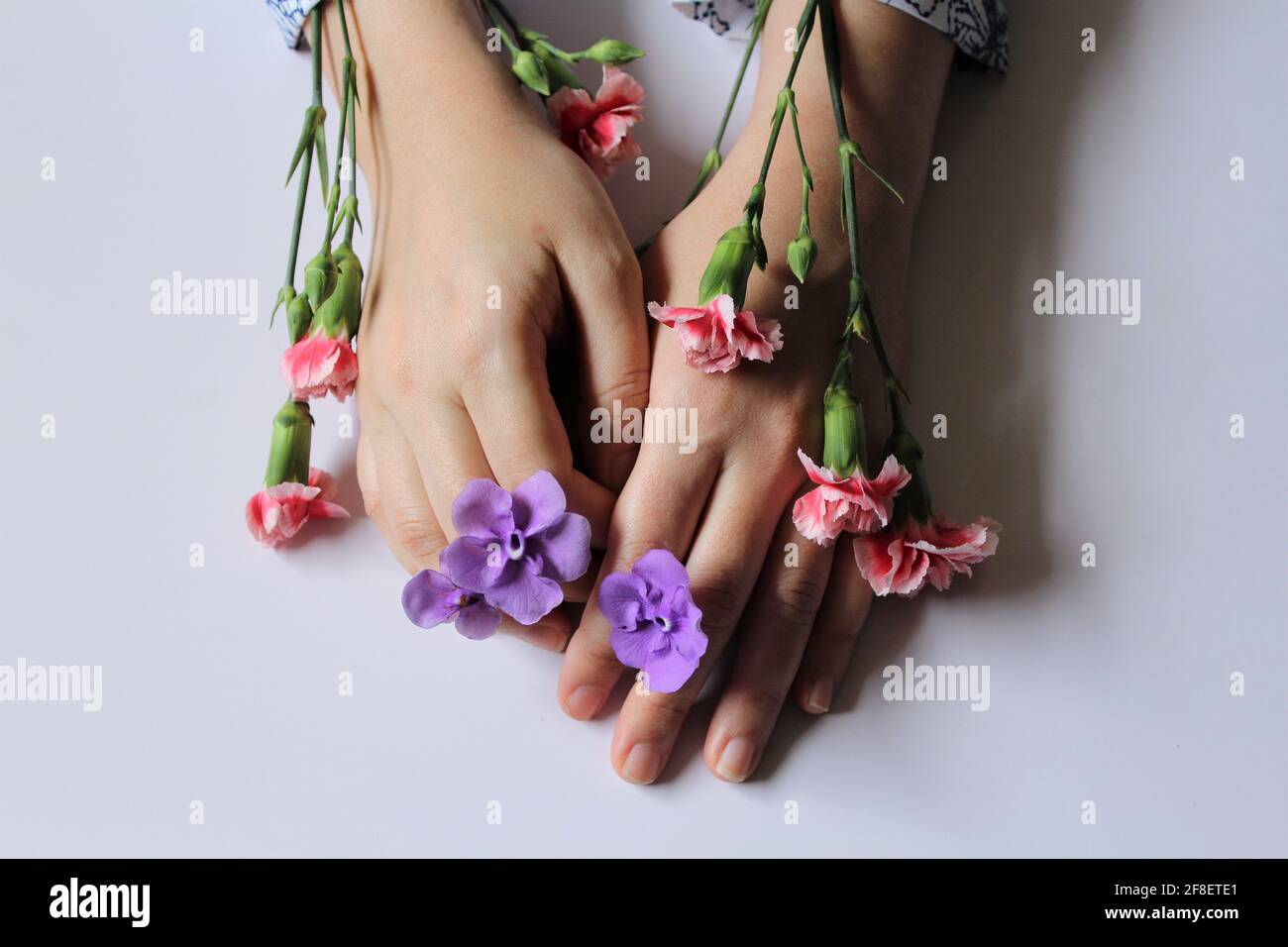 Woman's hands with flowers entangled through her fingers. Close-up ...