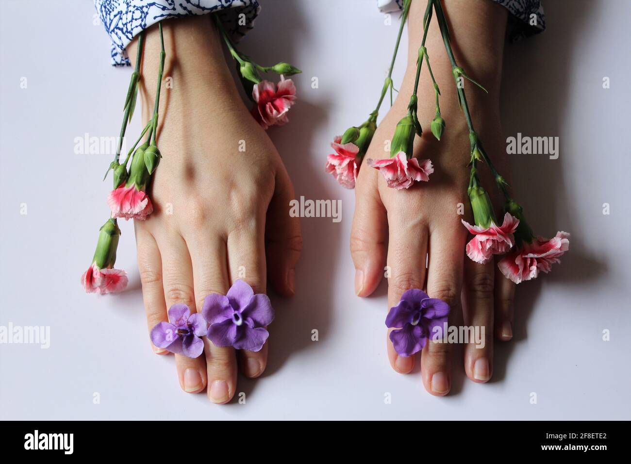 Womans hands with flowers entangled through her fingers. Closeup ...