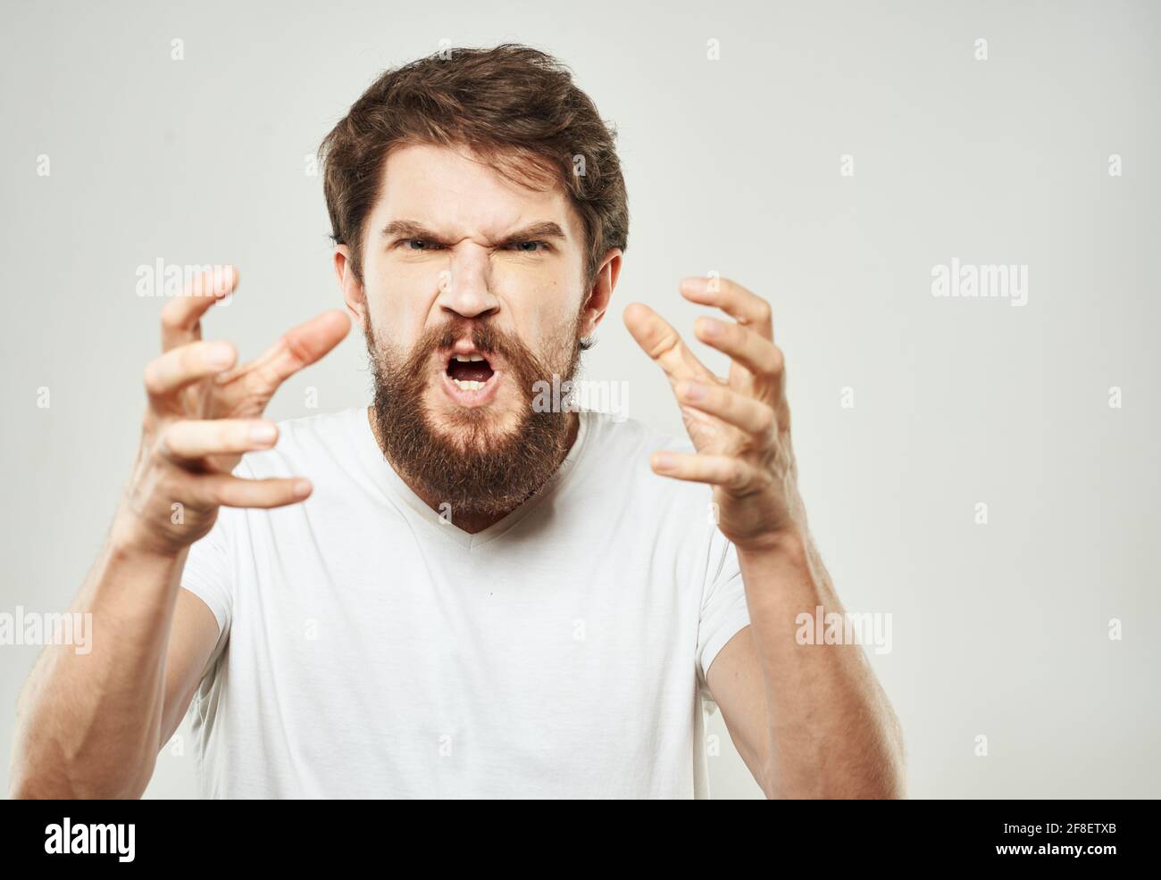 Aggressive man gestures with his hands on a light background stress ...