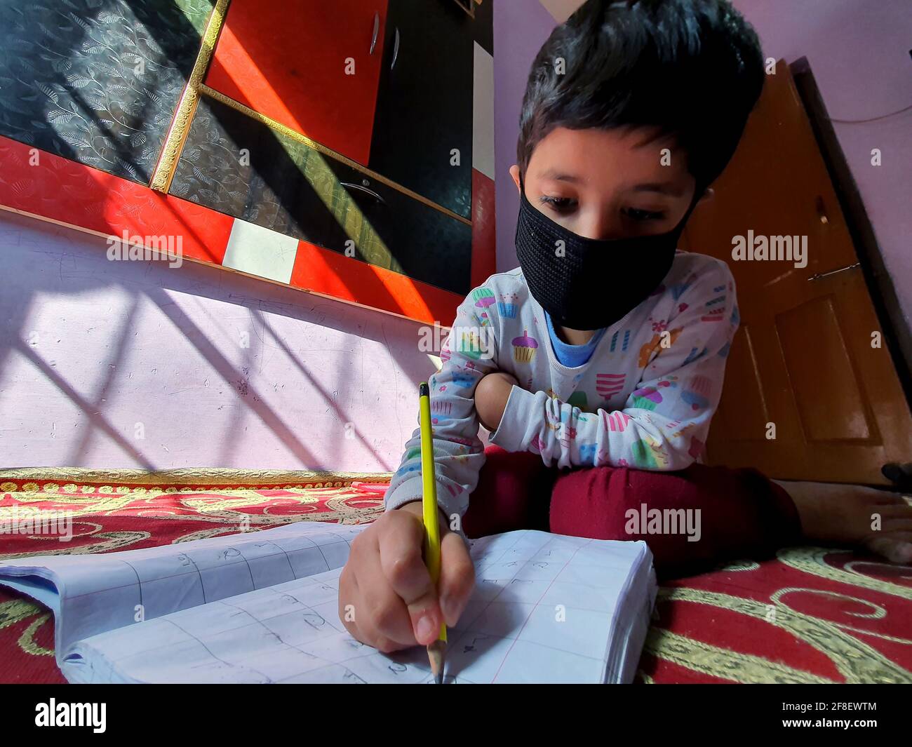 Masked students reading and writing their school work at home during ...
