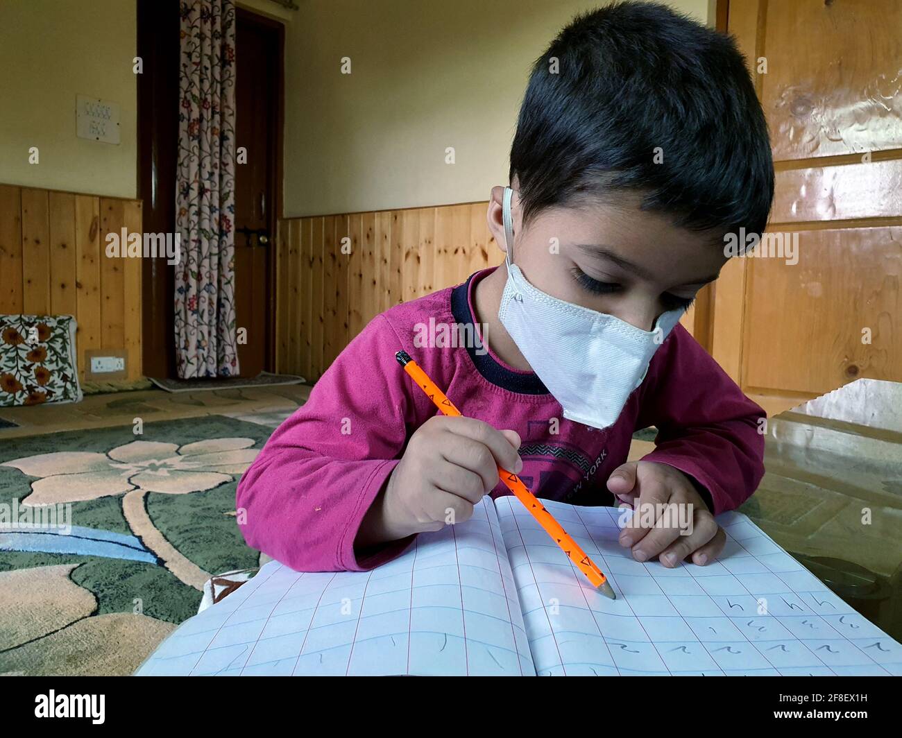 Masked students reading and writing their school work at home during ...