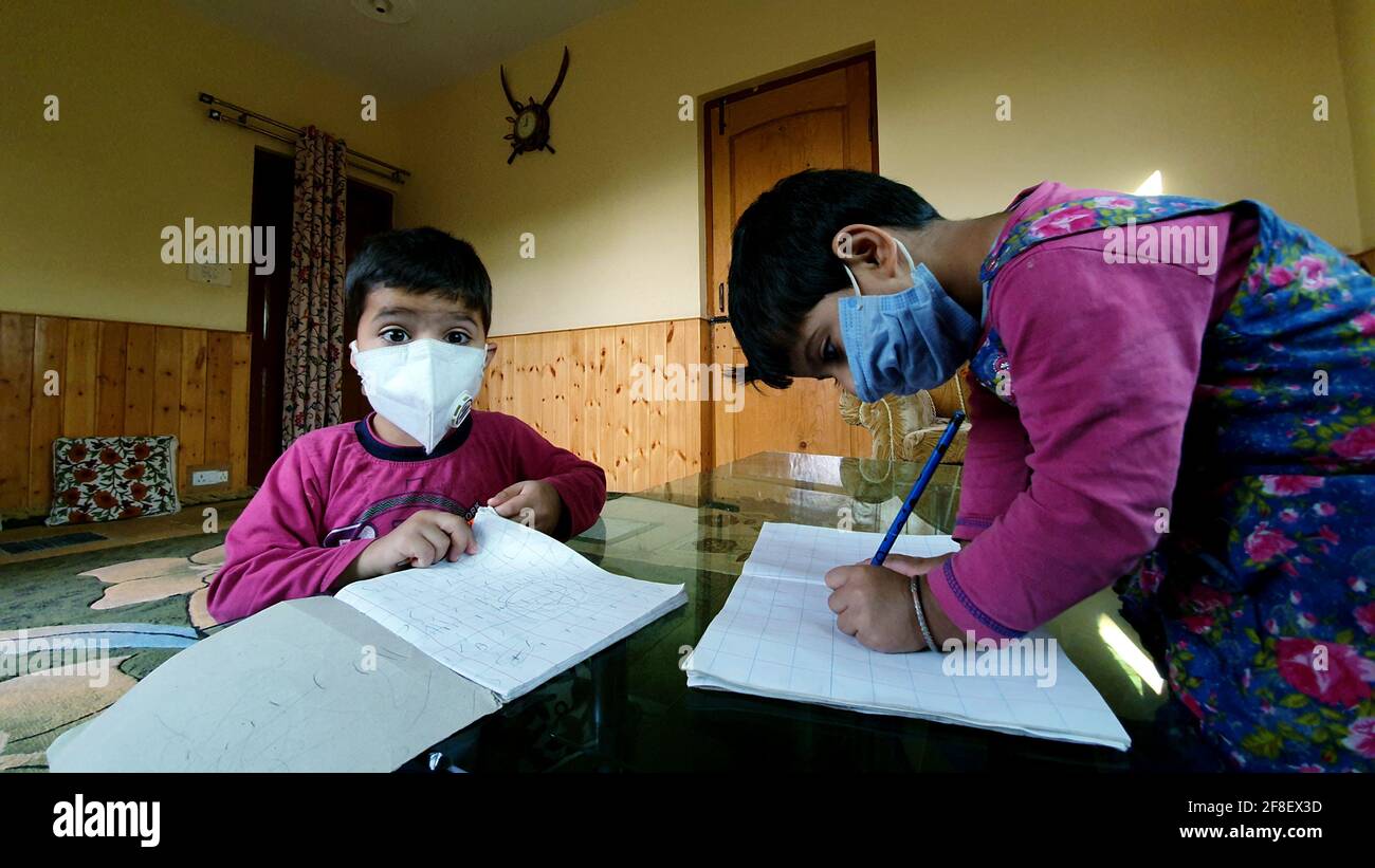 Masked students reading and writing their school work at home during ...