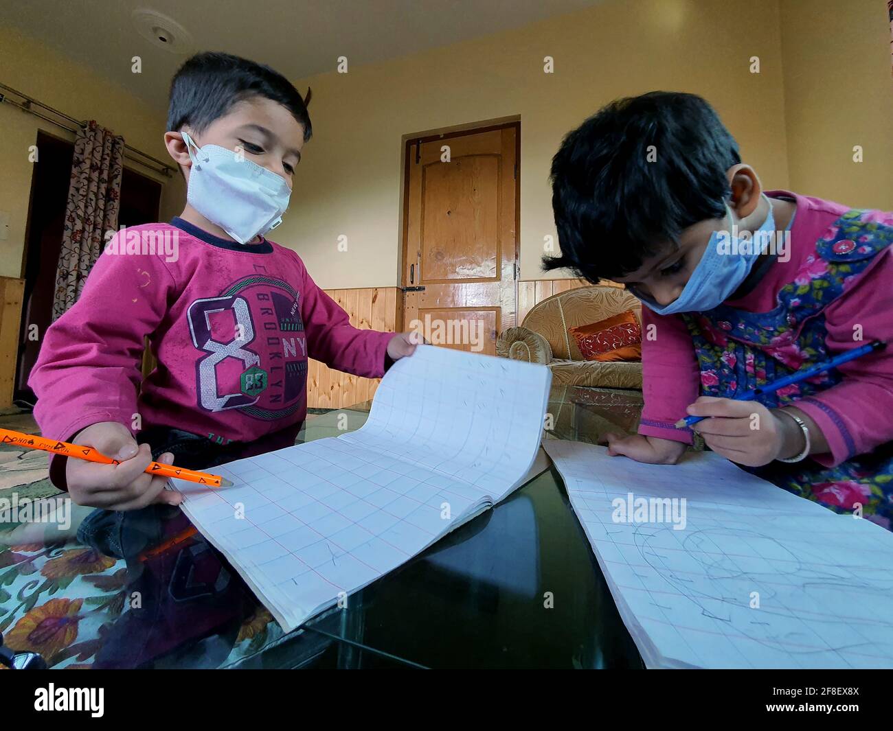 Masked students reading and writing their school work at home during ...