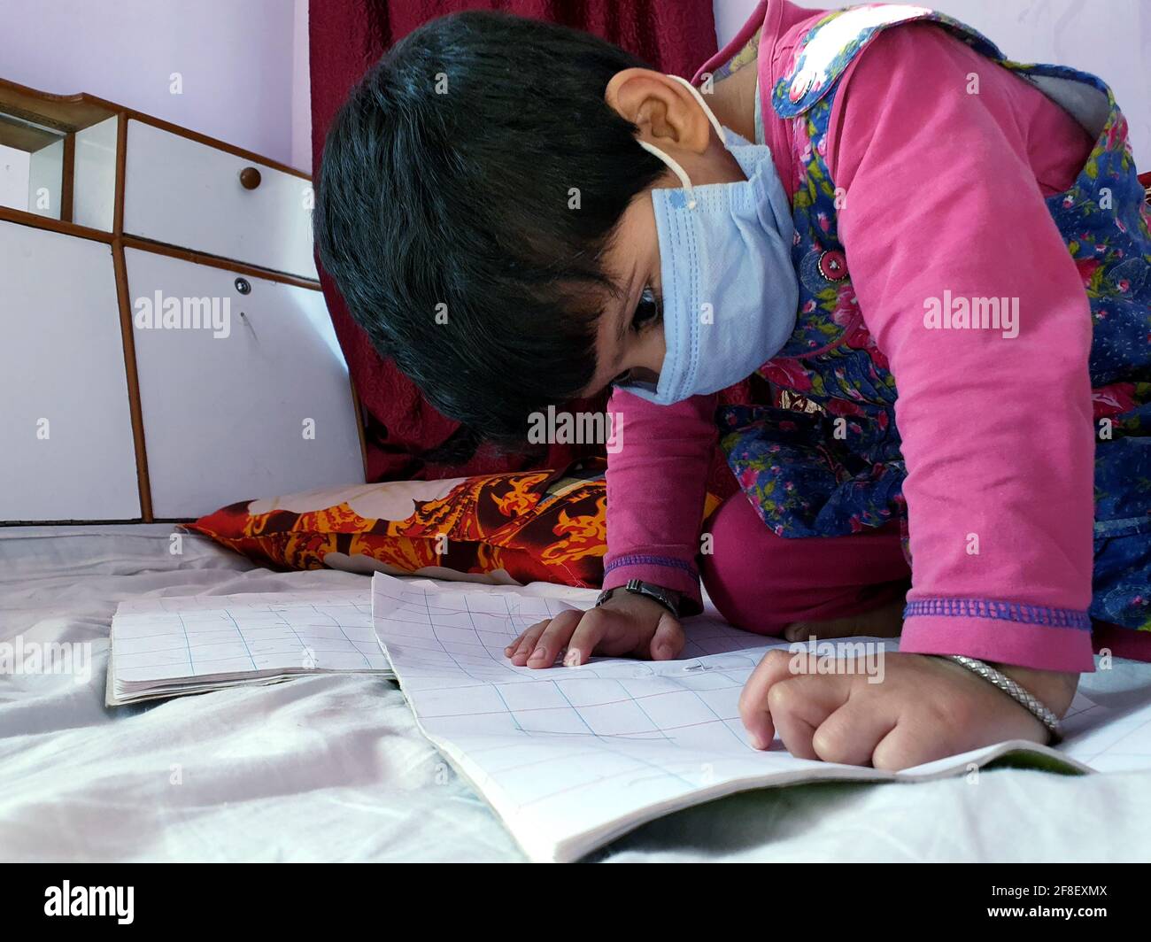 Masked students reading and writing their school work at home during ...