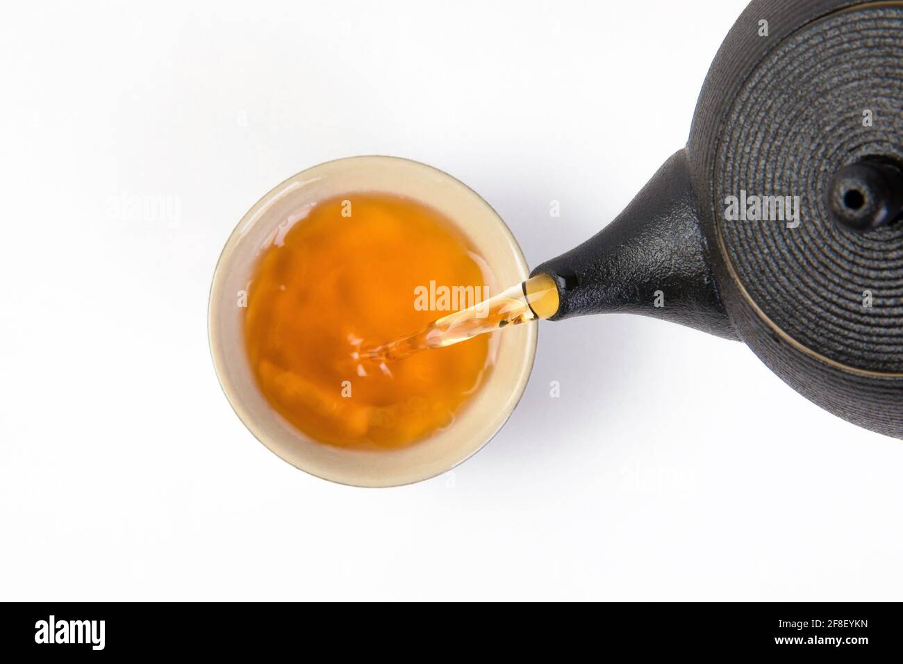 Overhead shot hot tea being poured from a teapot to a ceramic teacup ...