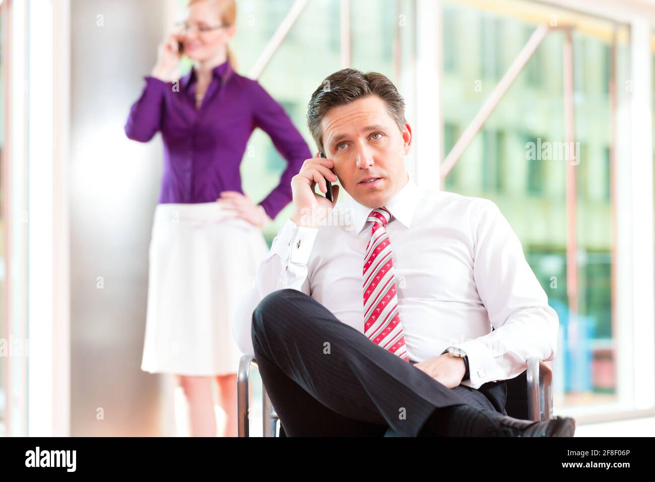 Business people - boss and secretary in office, he is sitting and she ...