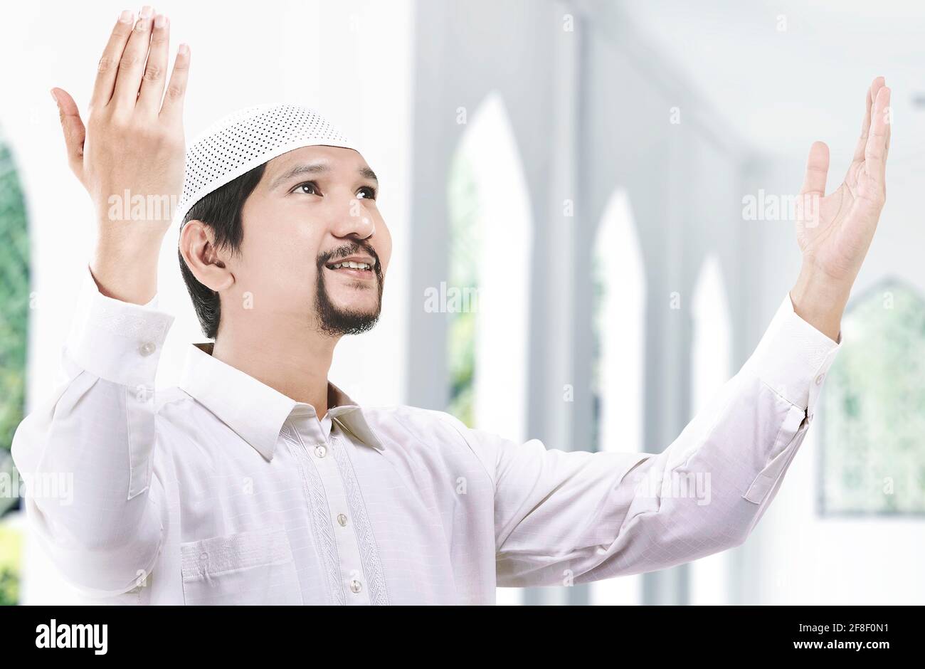 Asian Muslim man standing while raised hands and praying on the mosque ...