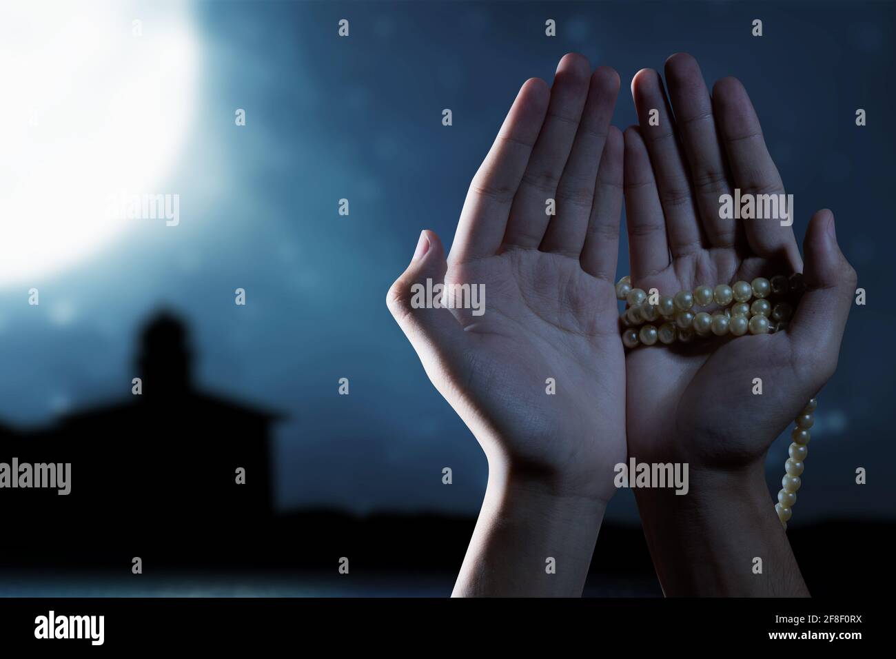 Muslim man praying with prayer beads on his hands with the night scene ...