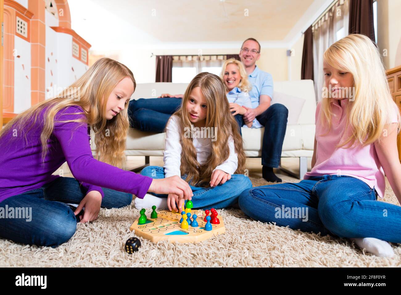 Family playing board game ludo at home on the floor Stock Photo - Alamy